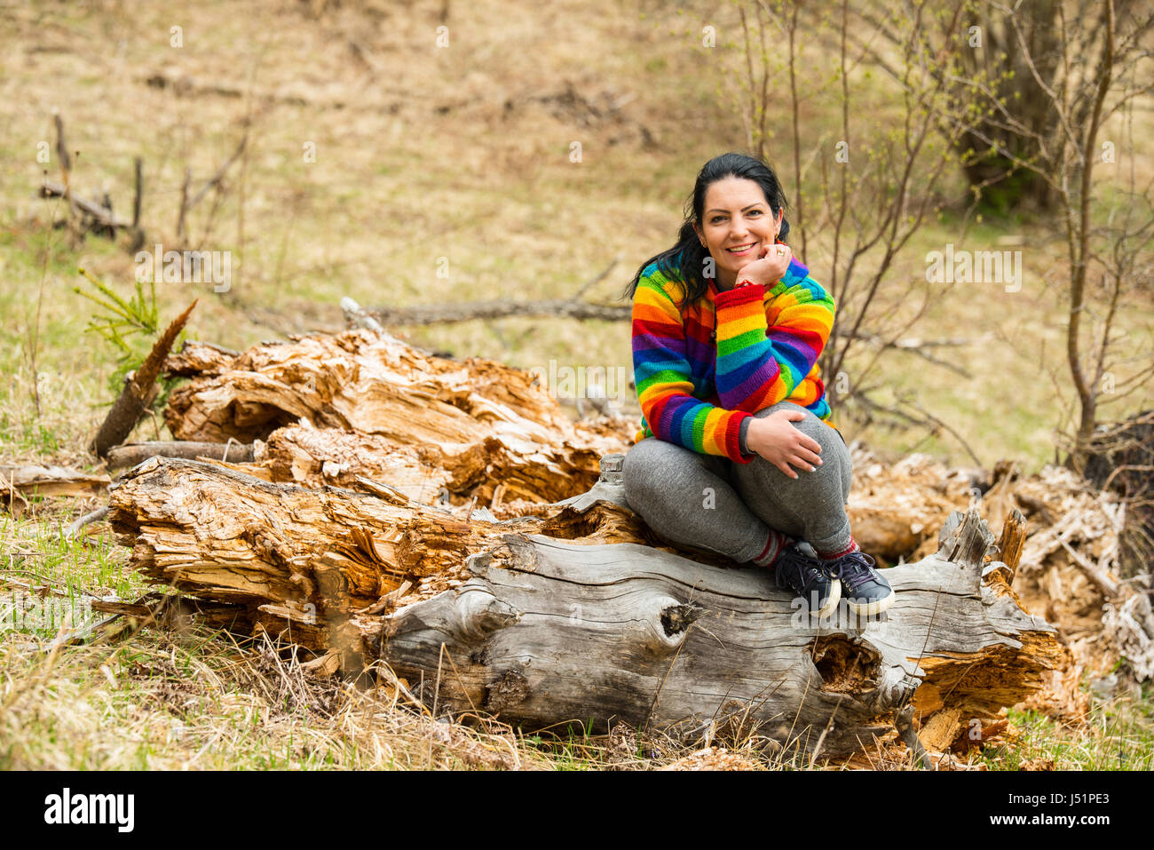 Cheerful female sitting on a bark tree in nature Stock Photo - Alamy