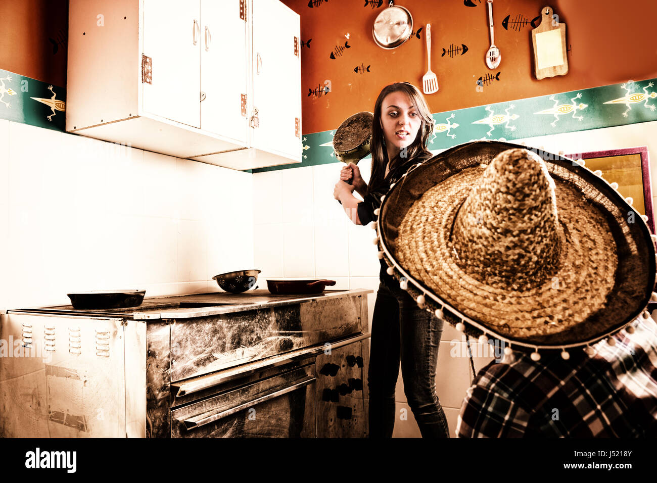 Young angry woman brandishing a frying pan at a man in sombrero while ...