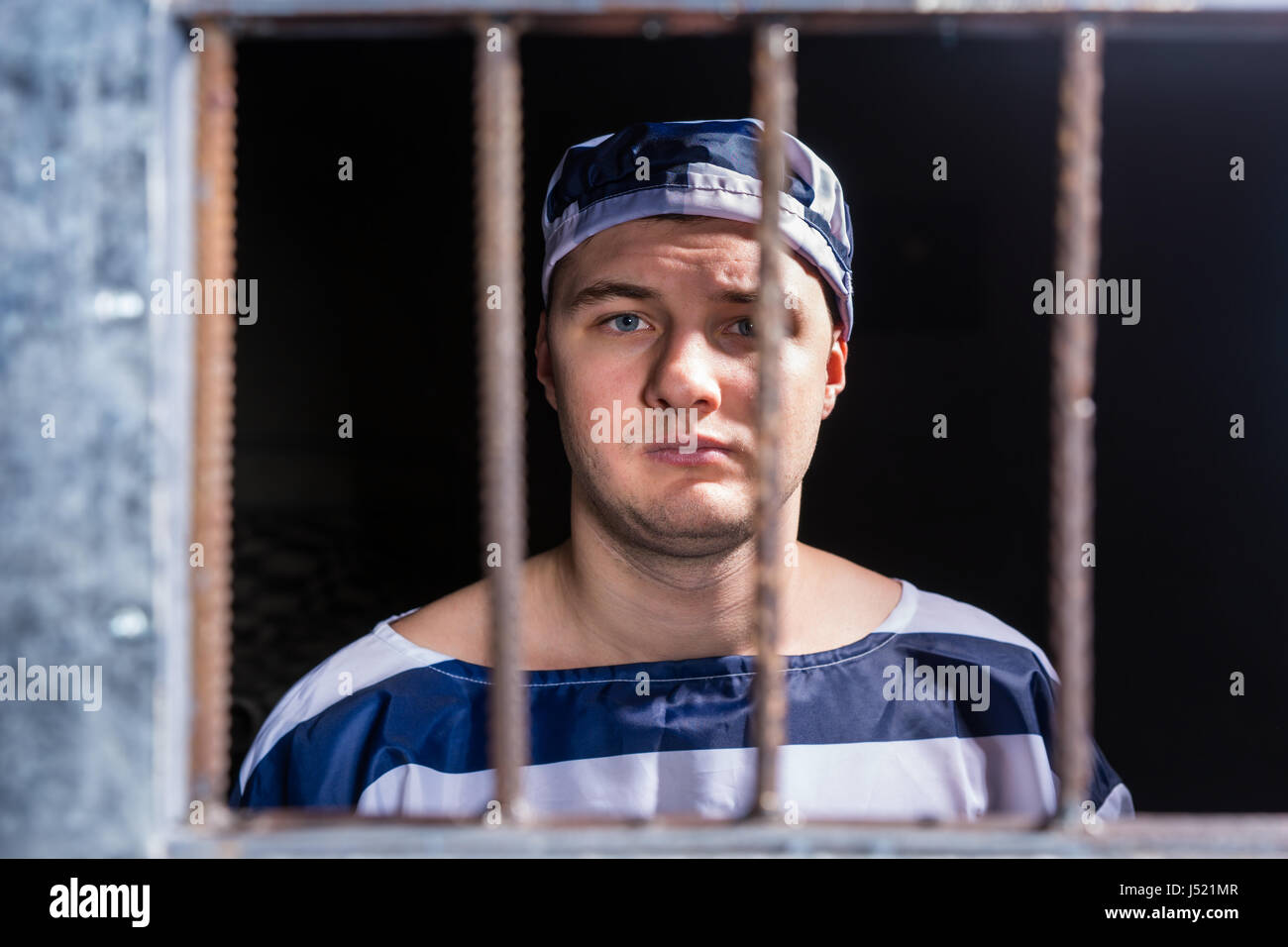 Portrait of young male prisoner wearing prison uniform standing behind ... Portrait of young male prisoner wearing prison uniform standing behind ...