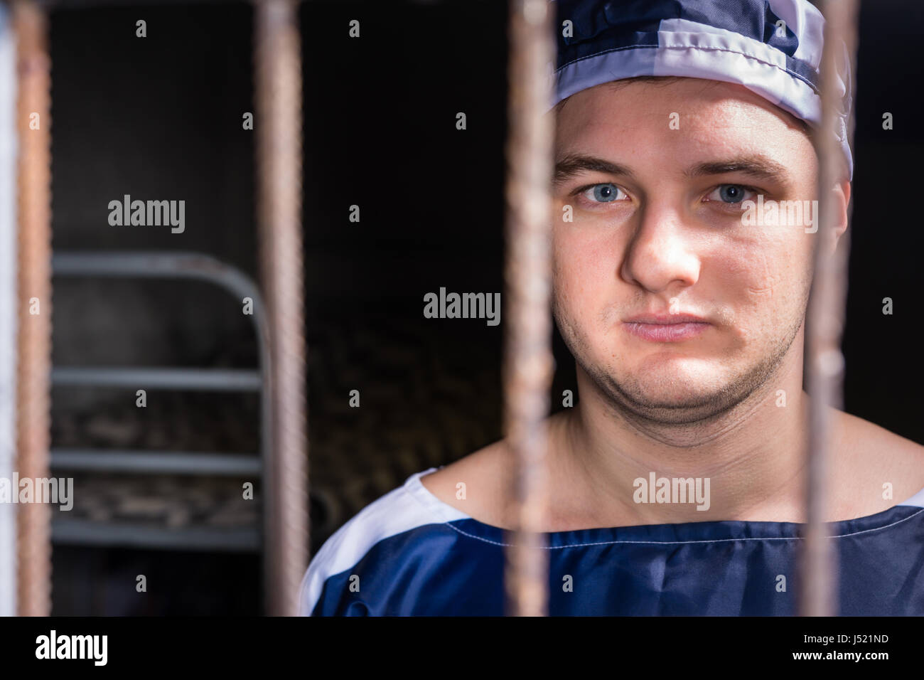 Portrait of young male prisoner wearing prison uniform standing behind ... Portrait of young male prisoner wearing prison uniform standing behind ...