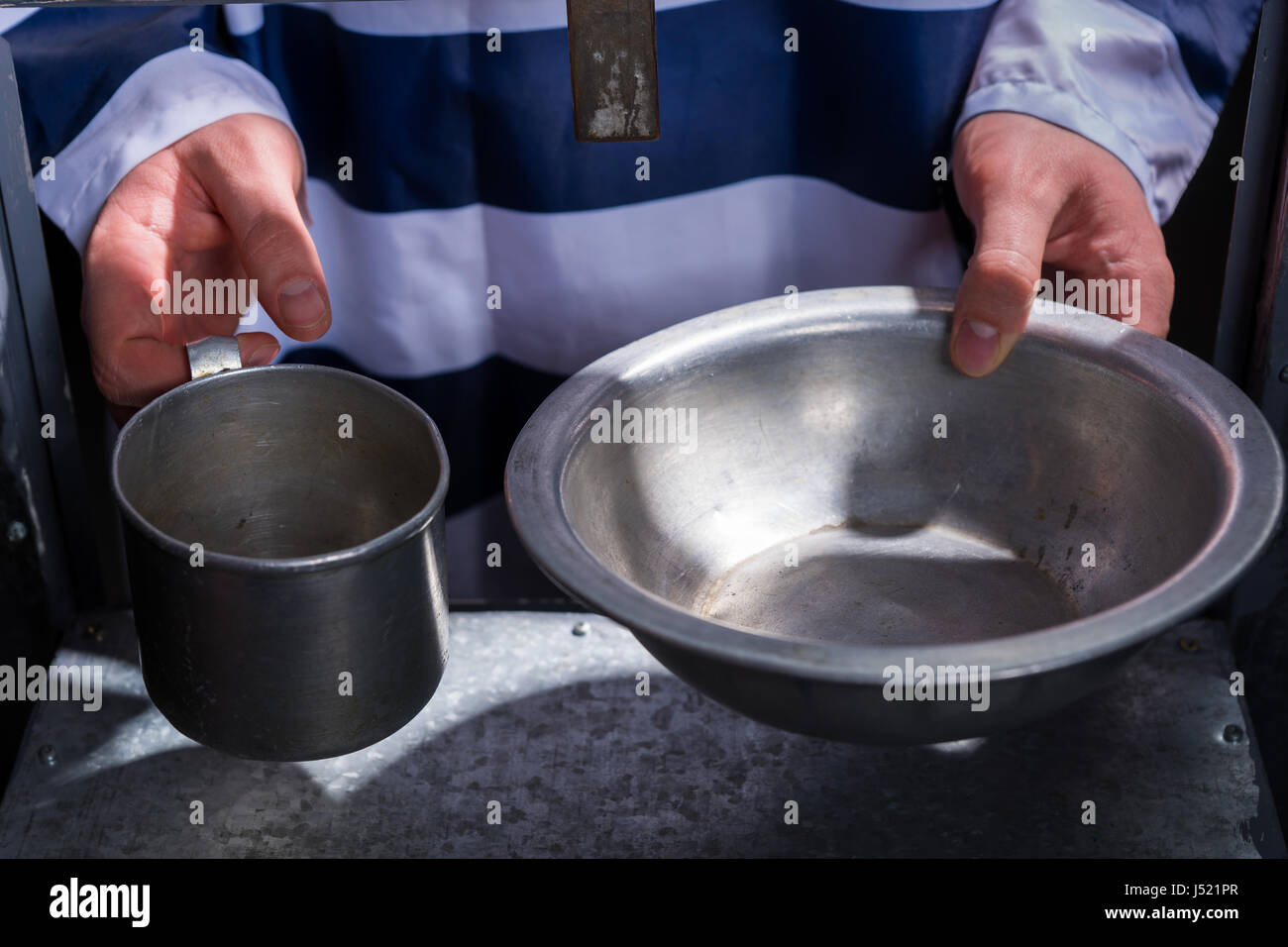Prisoner's hands holding aluminum dishes in a hole for supplying food ...