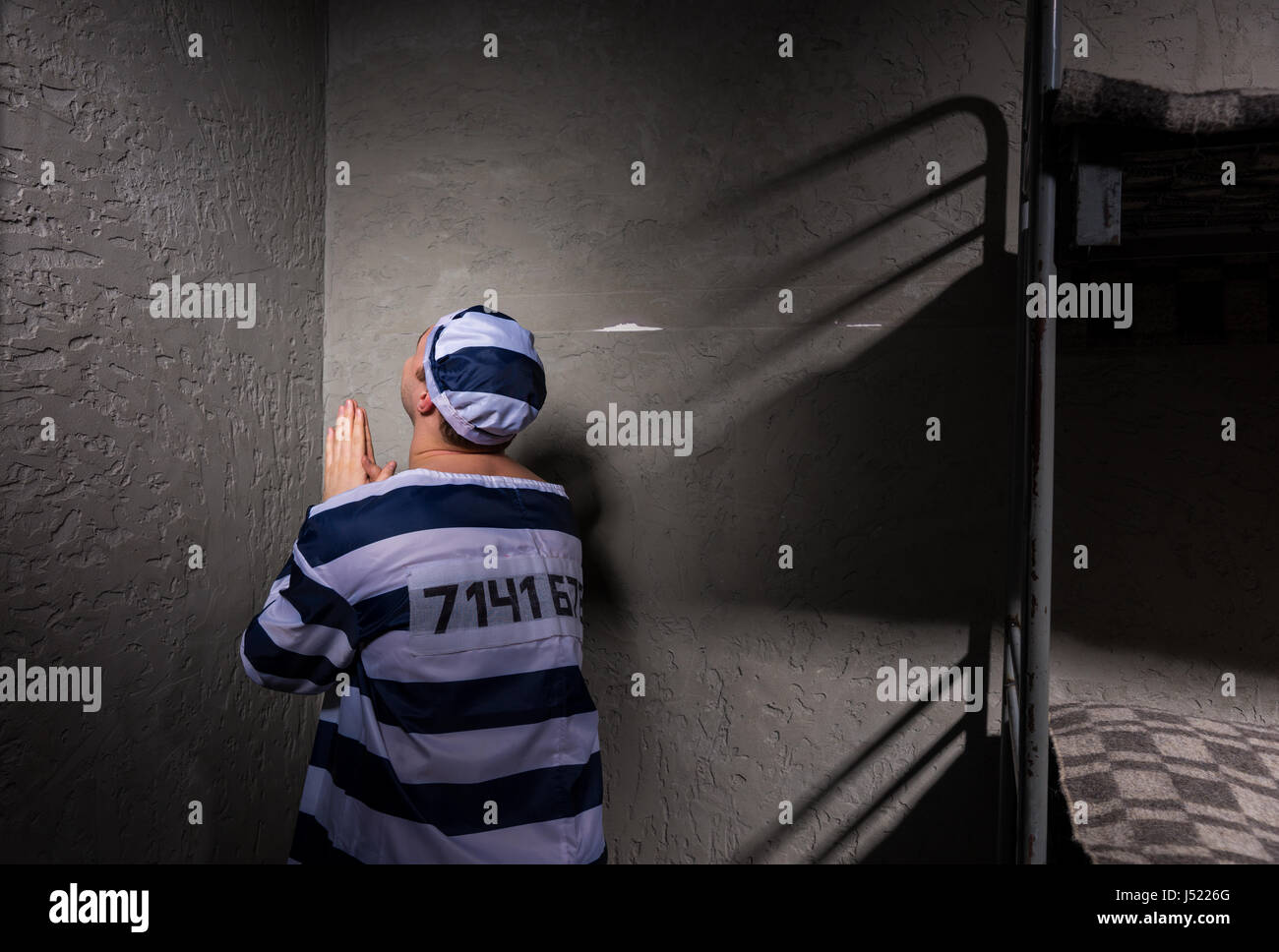 Prisoner wearing prison uniform with sewed number is sitting in the ...