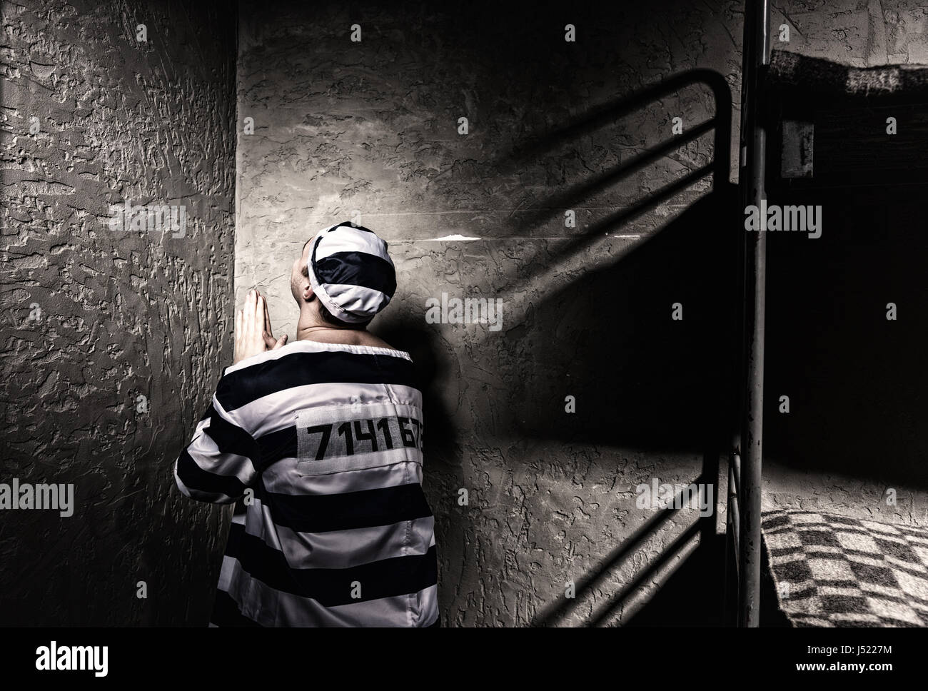 Male prisoner wearing prison uniform with sewed number is sitting in ...