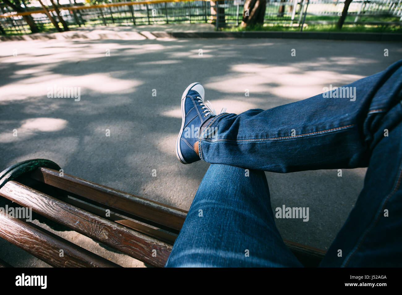 First-person view a man sitting on wooden bench in the park, wide angle ...
