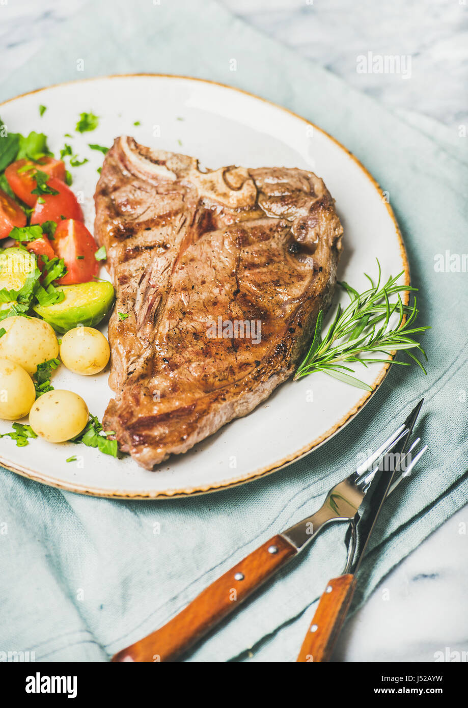 Grilled meat dinner plate. Cooked beef tbone steak with vegetables and ...
