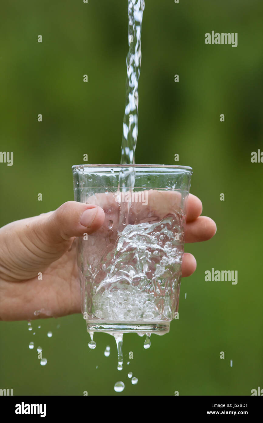 woman hand pouring clean natural water into glass on blurred background Stock Photo - Alamy