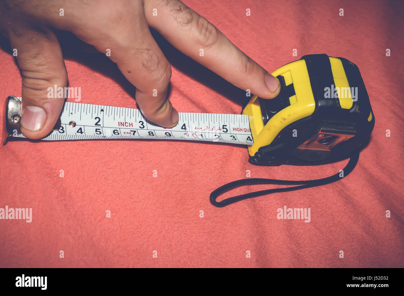 man measuring with tape measure on red background Stock Photo - Alamy
