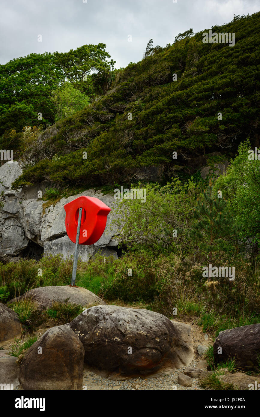 Orange lifebuoy stand mounted on a rock at lake shore in Killarney ...