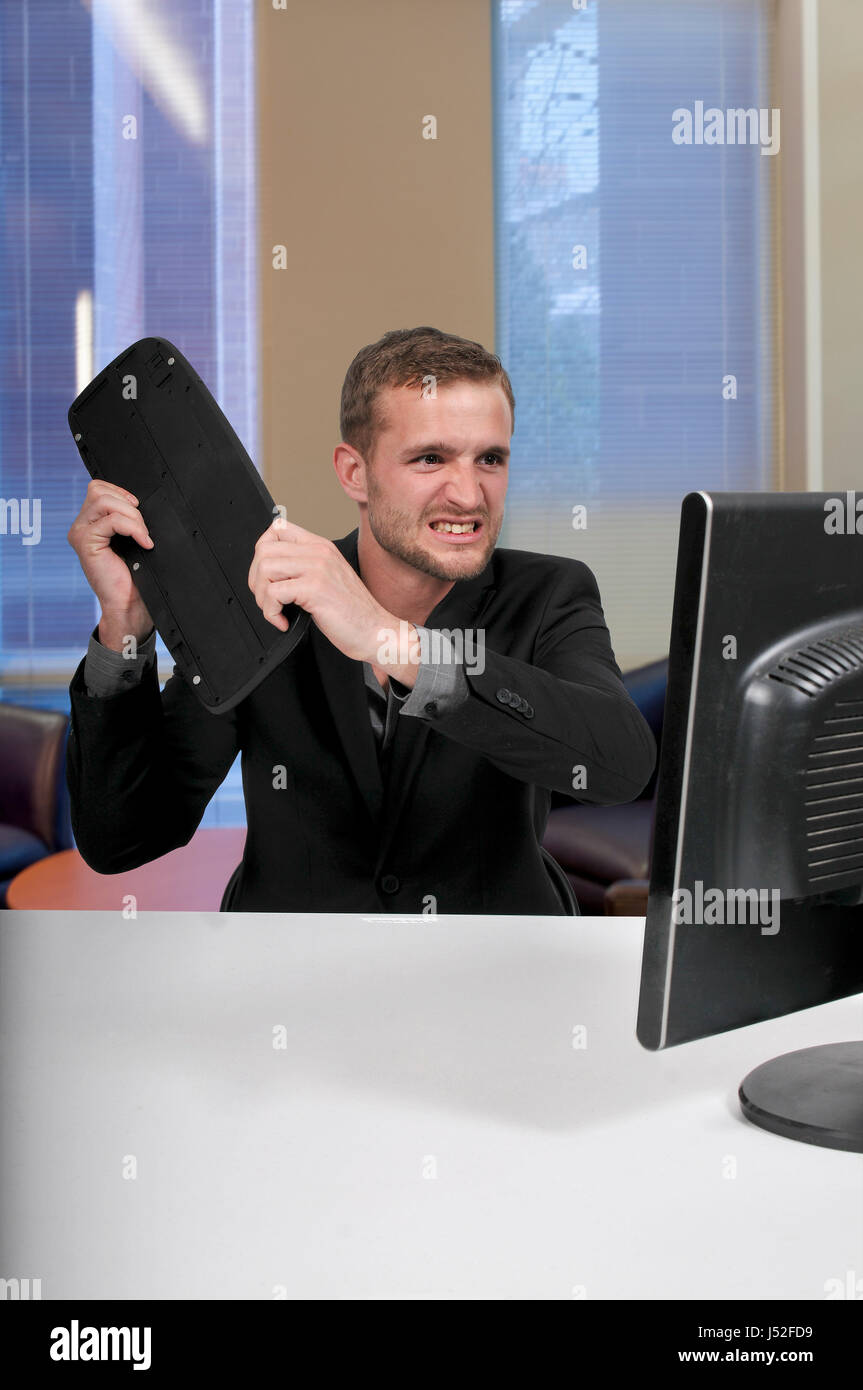 Angry man using a desktop computer for business Stock Photo - Alamy