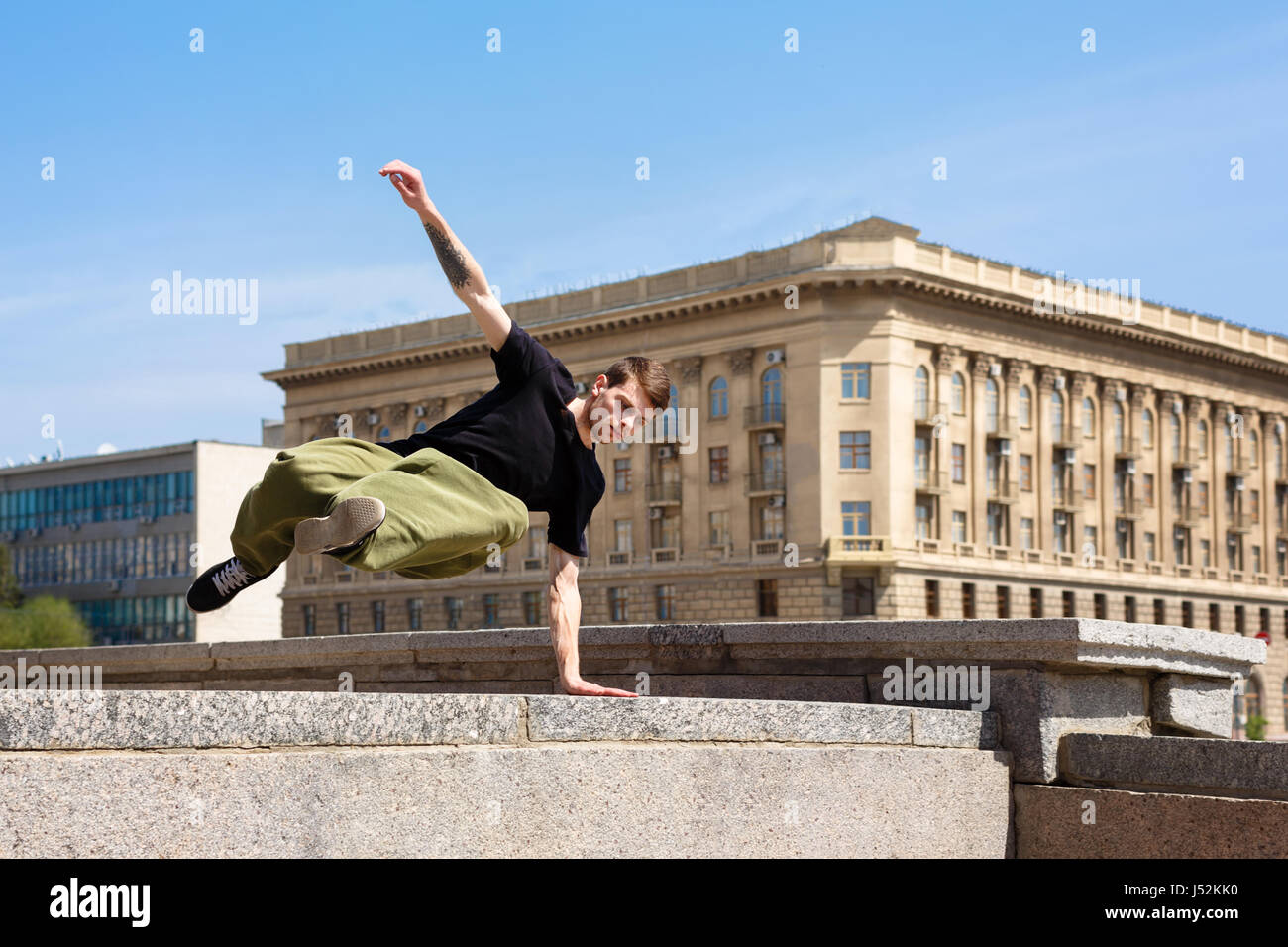 Young man jumping over the wall. Parkour in the urban space. Sport in ...