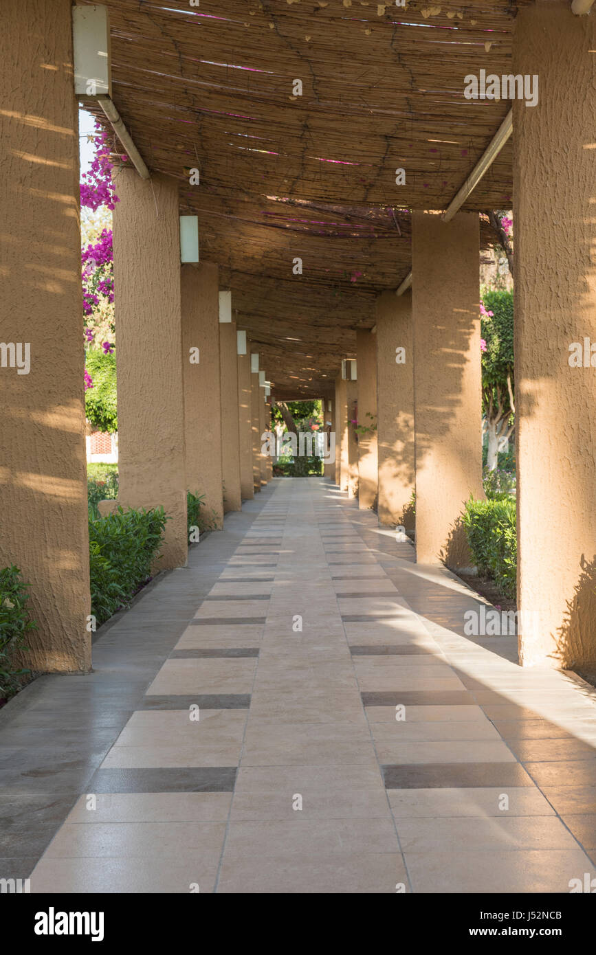 Covered tiled paved footpath pathway with stone columns in rural formal ...