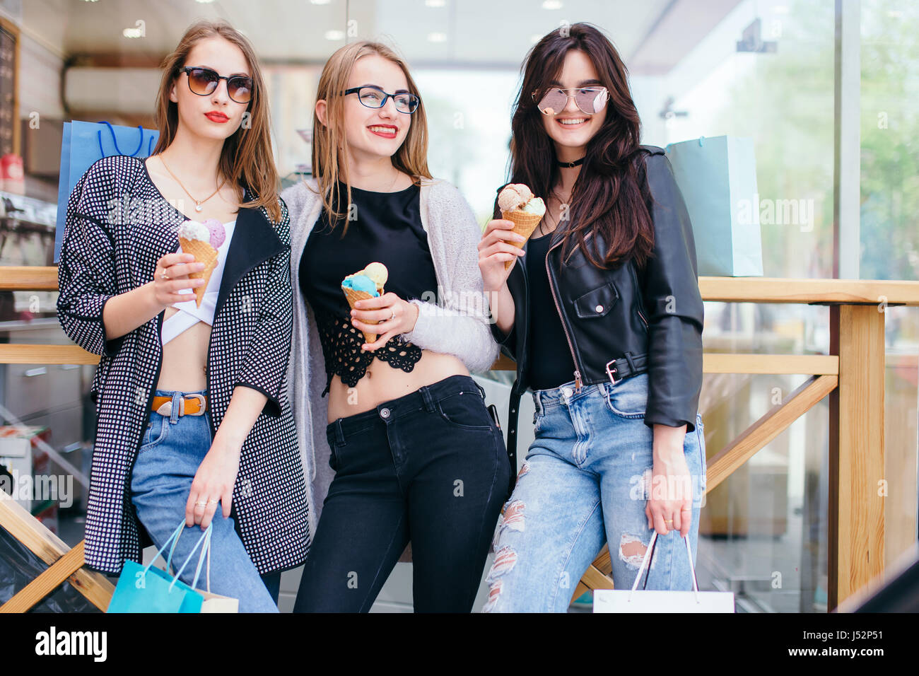 Three girls with shopping bags on park blur background Stock Photo - Alamy