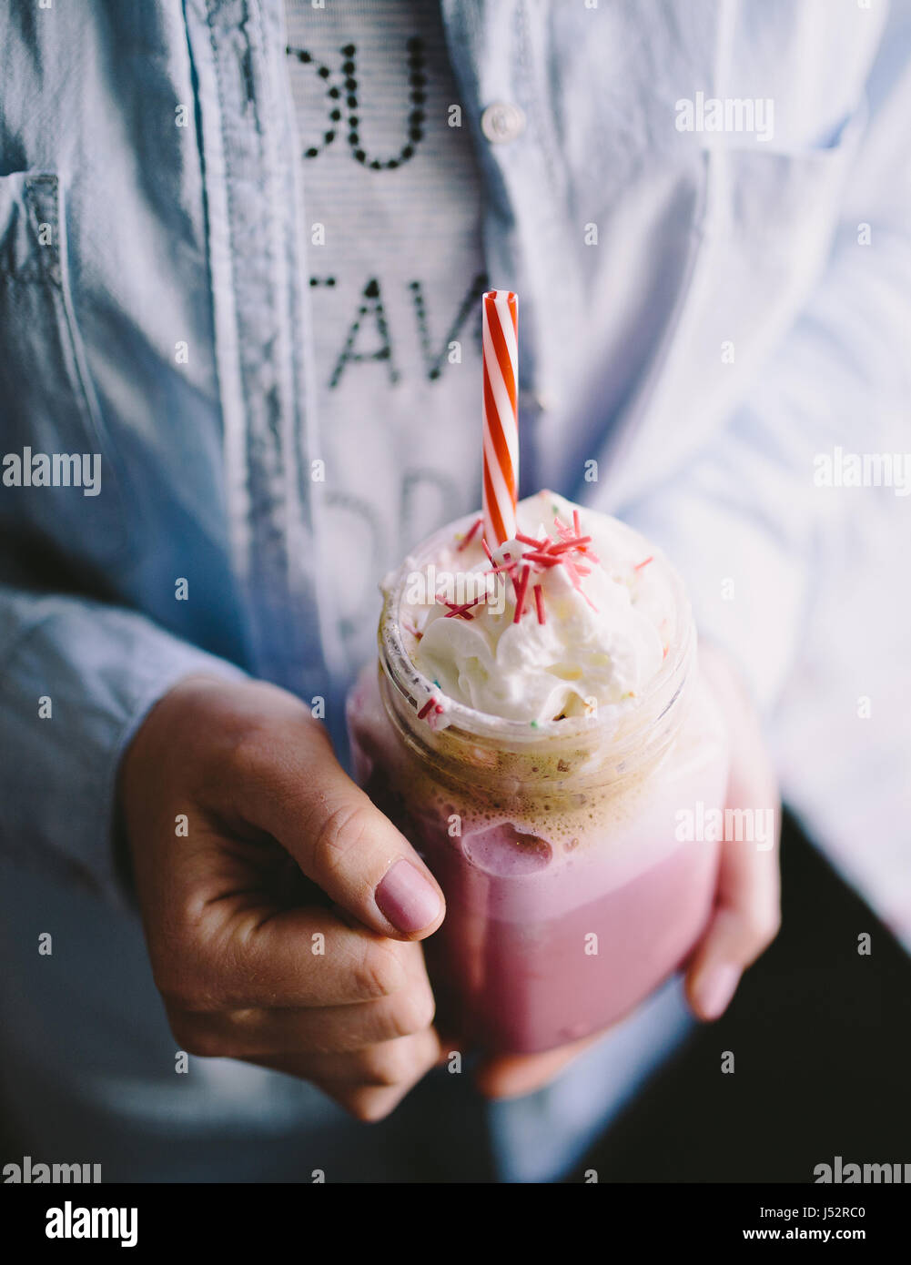 Girl is holding stylized mason jar cup of pink coffee with cream ...