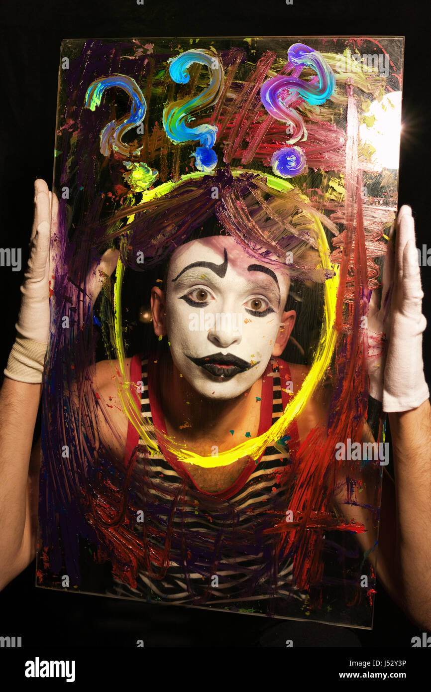 Face of Mime behind glass with multi-colored stains and question marks ...