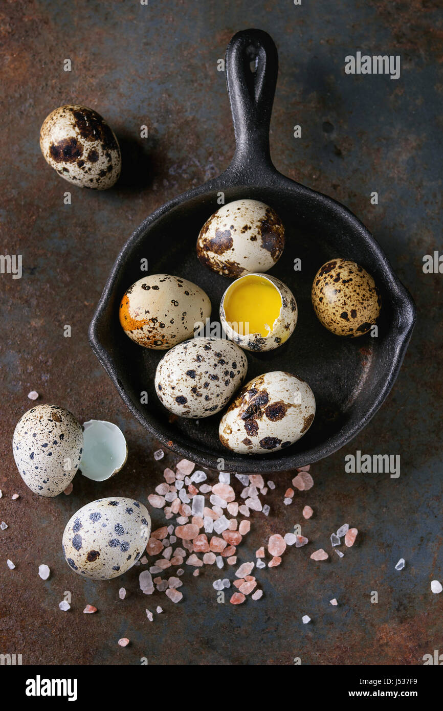 Whole and broken quail eggs with yolk in shell and pink sea salt ...
