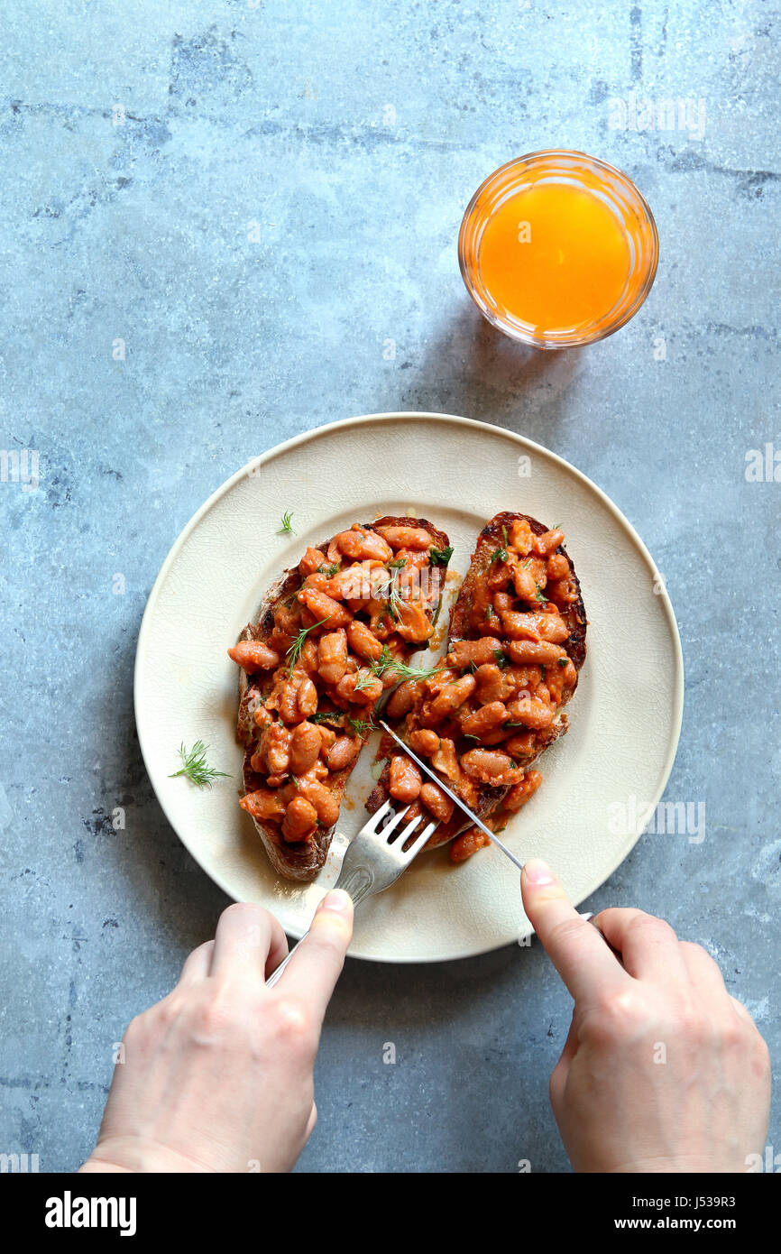 Female eating beans on toast served with a glass of orange juice Stock ...