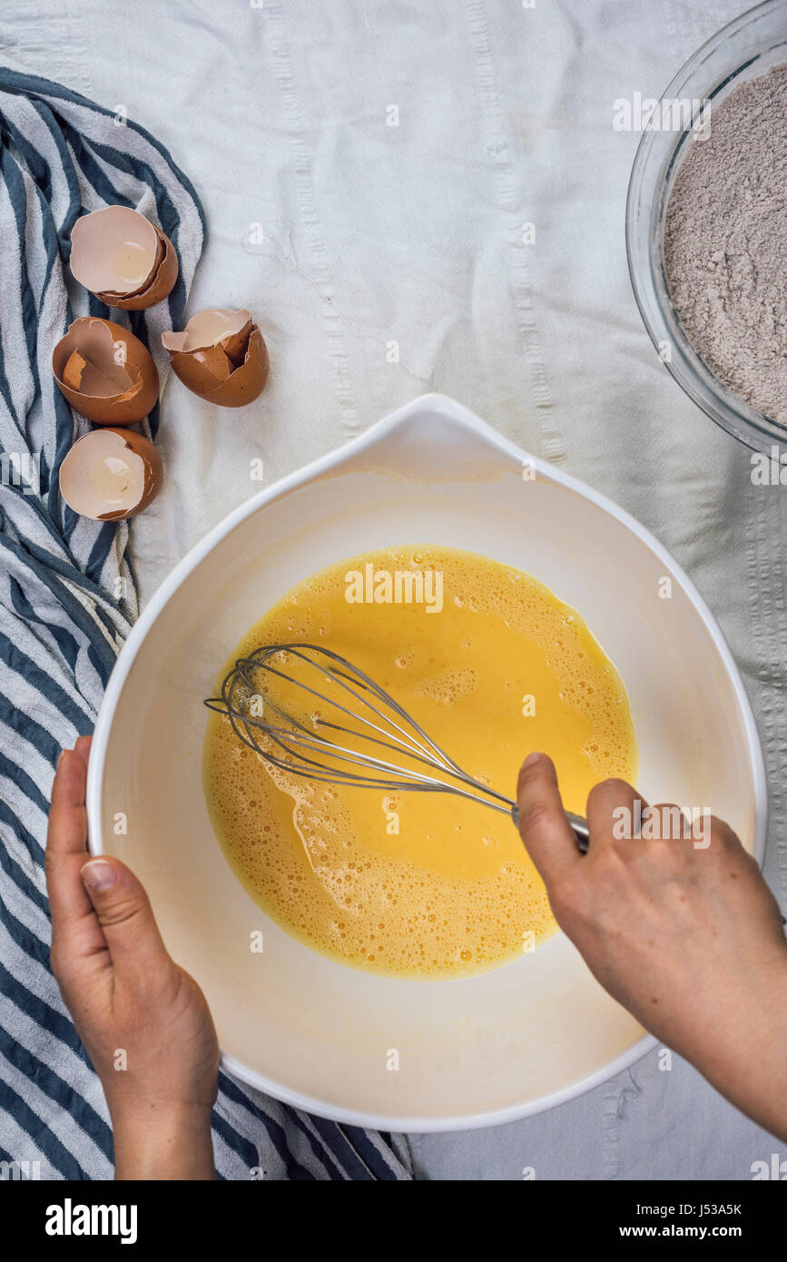 A woman whisking eggs in large bowl photographed from top view. Egg ...