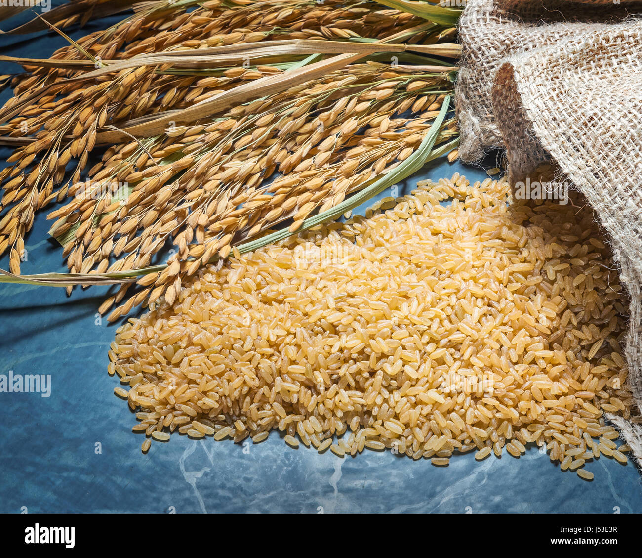 Brown rice uncooked in a bag with a pile of brown rice and spike rice ...