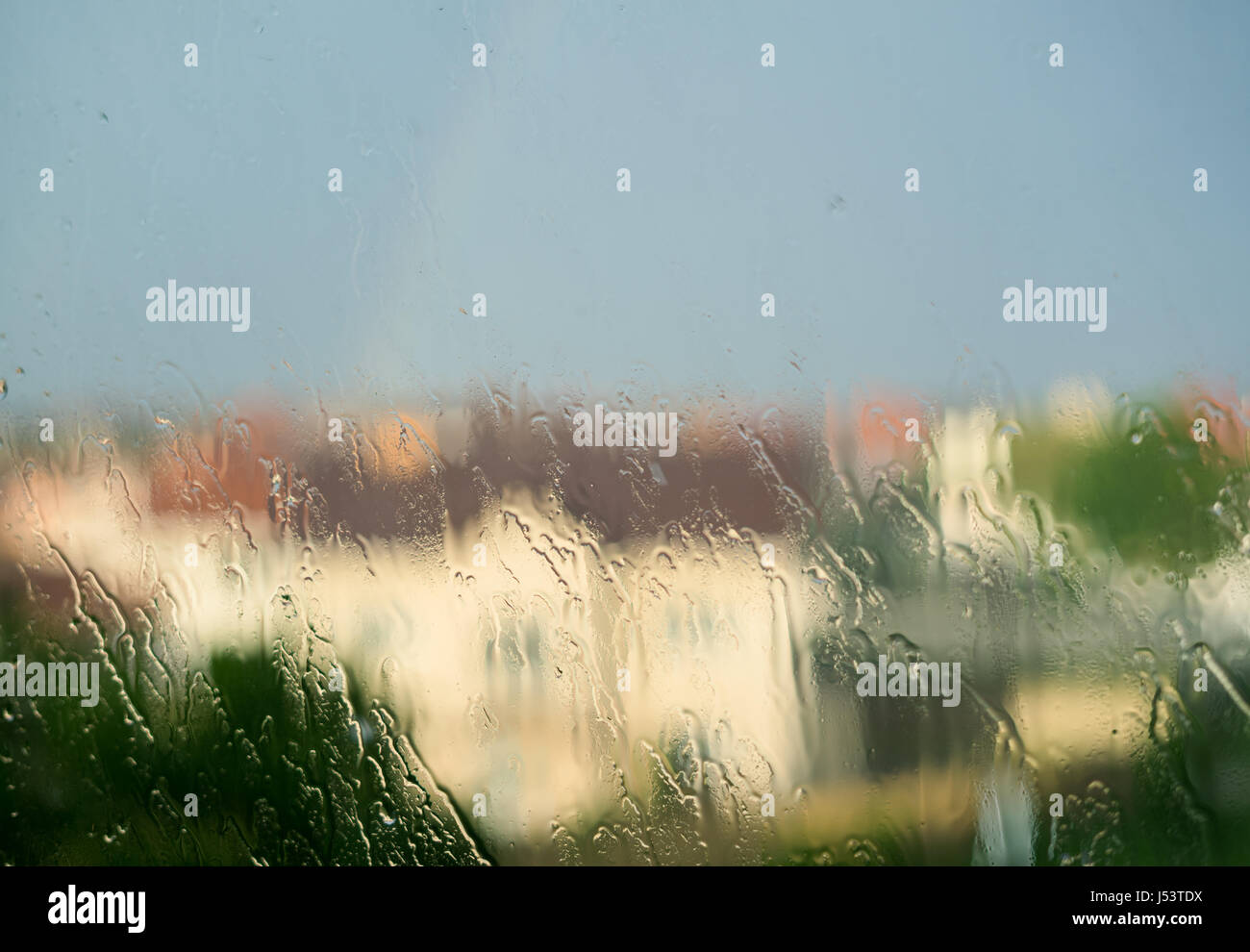 Rain drops on window during rain with houses on background Stock Photo ...