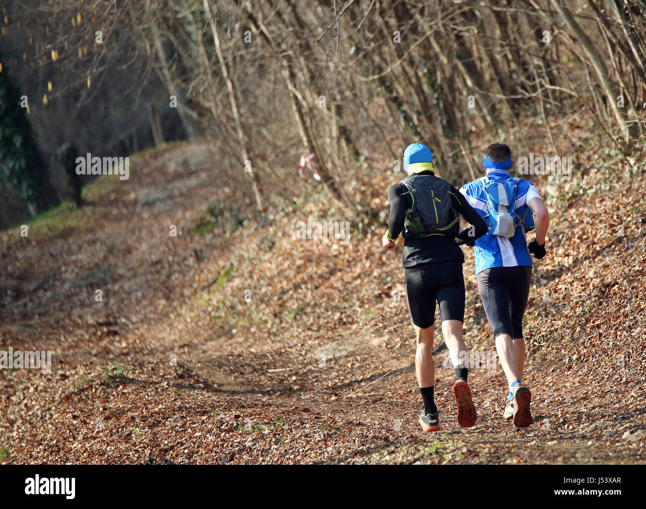Two runners from behind run along the mountain trail during the racing ...