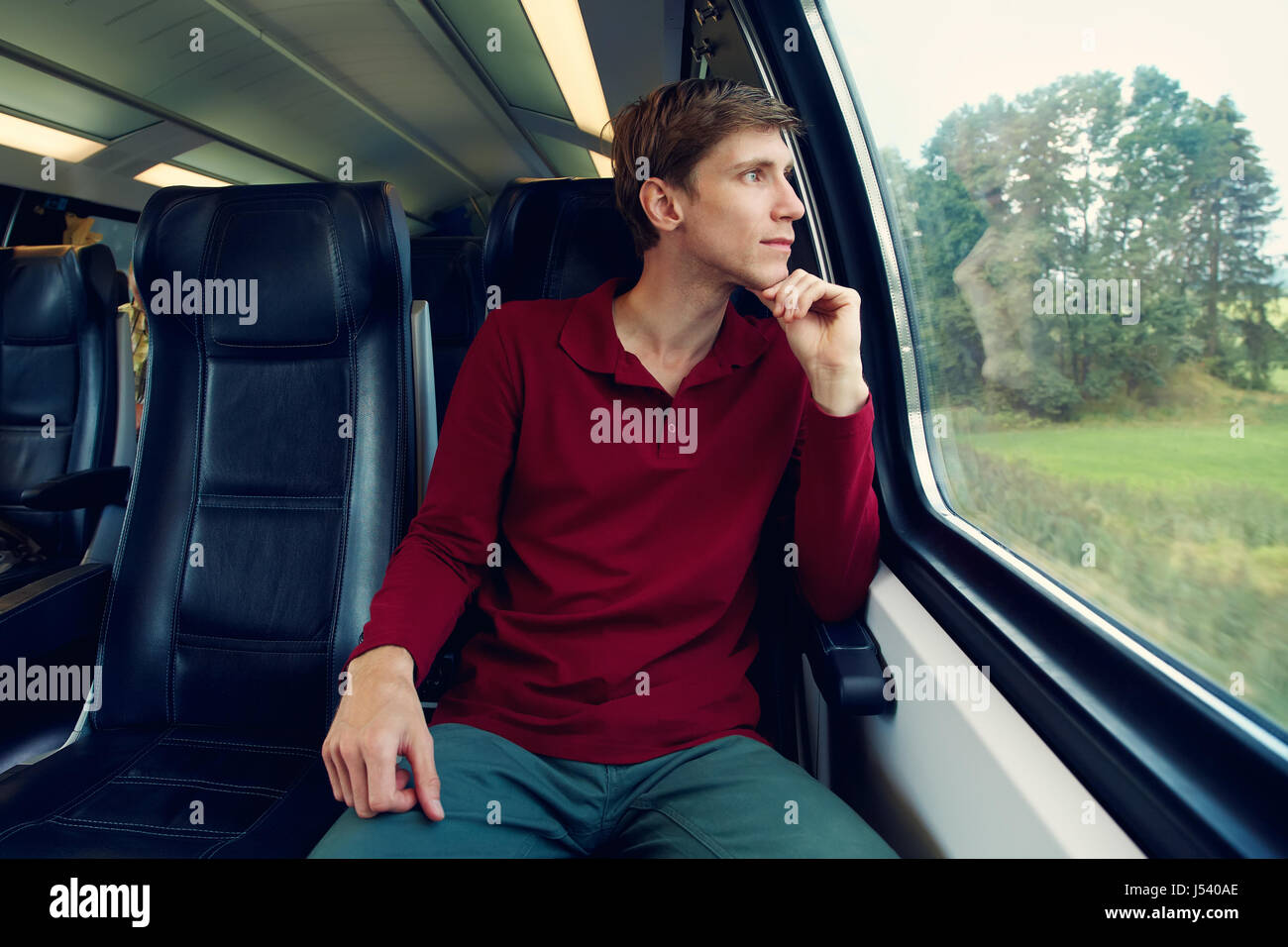 handsome man riding on a train and looking out the window. traveler on ...