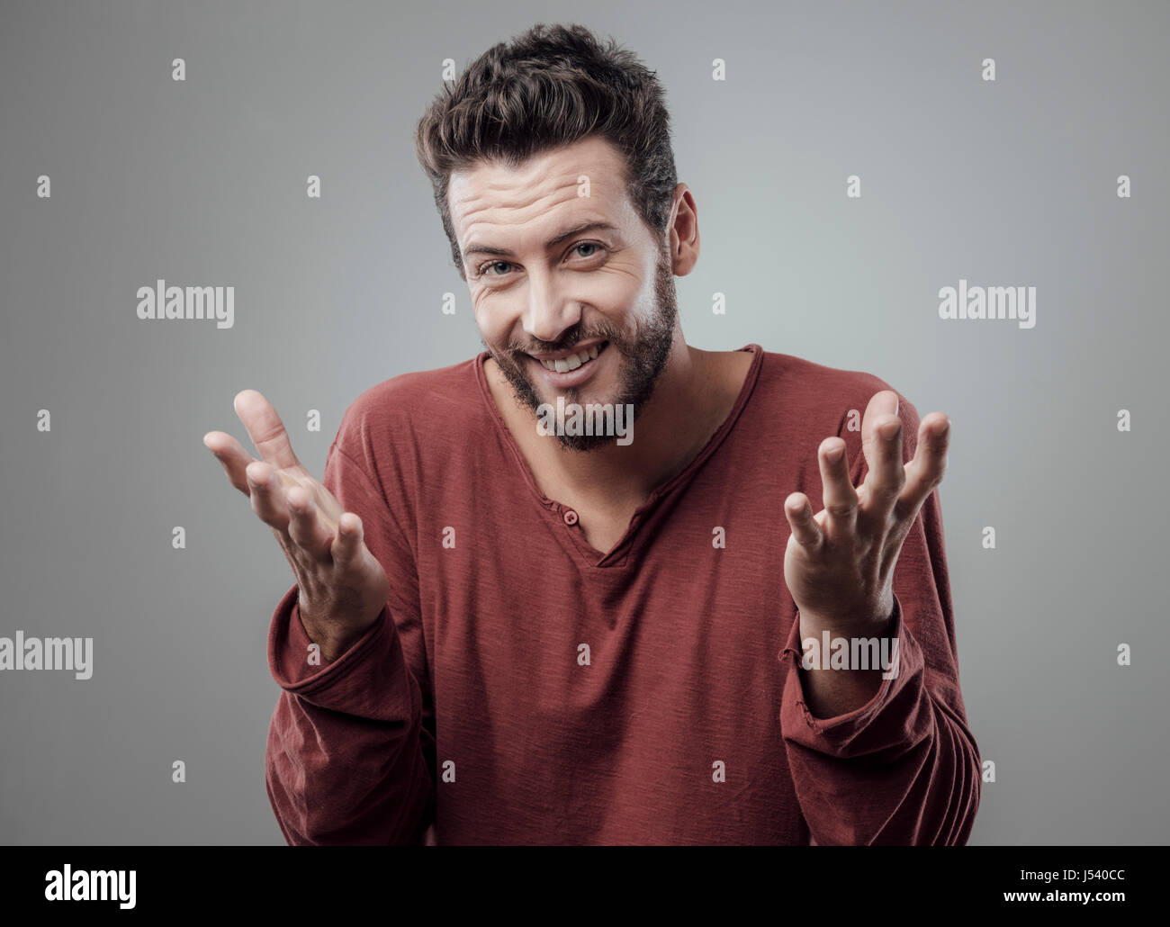 Confused young man shrugging and smiling at camera Stock Photo - Alamy