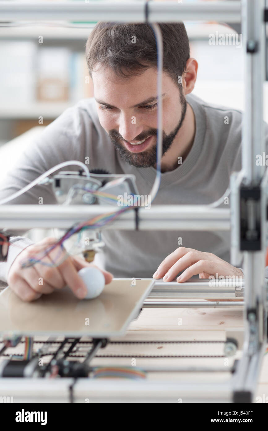 Young designer engineer using a 3D printer in the laboratory and ...