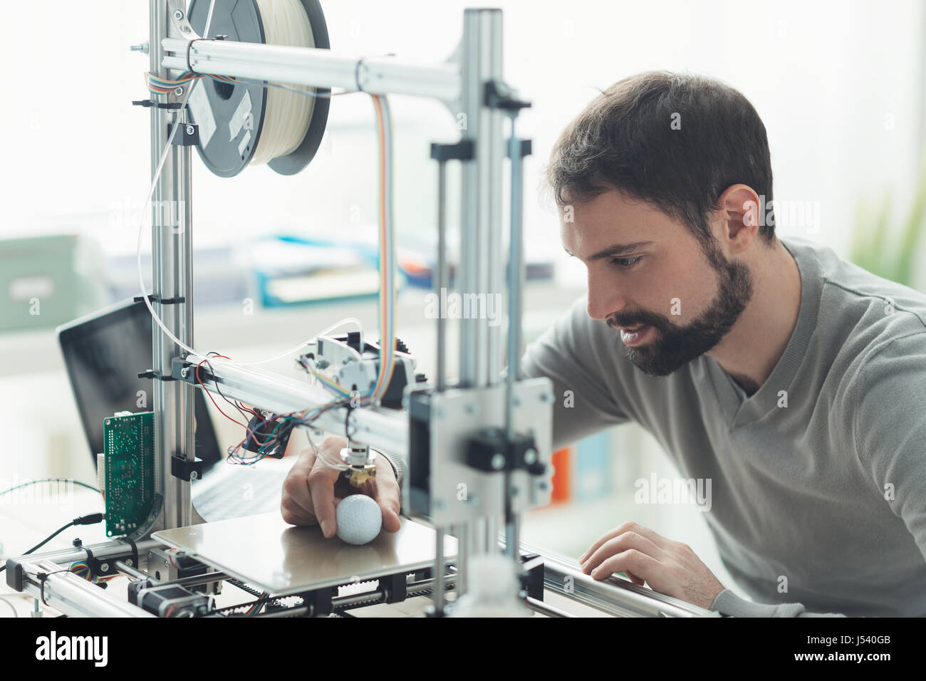 Young designer engineer using a 3D printer in the laboratory and ...