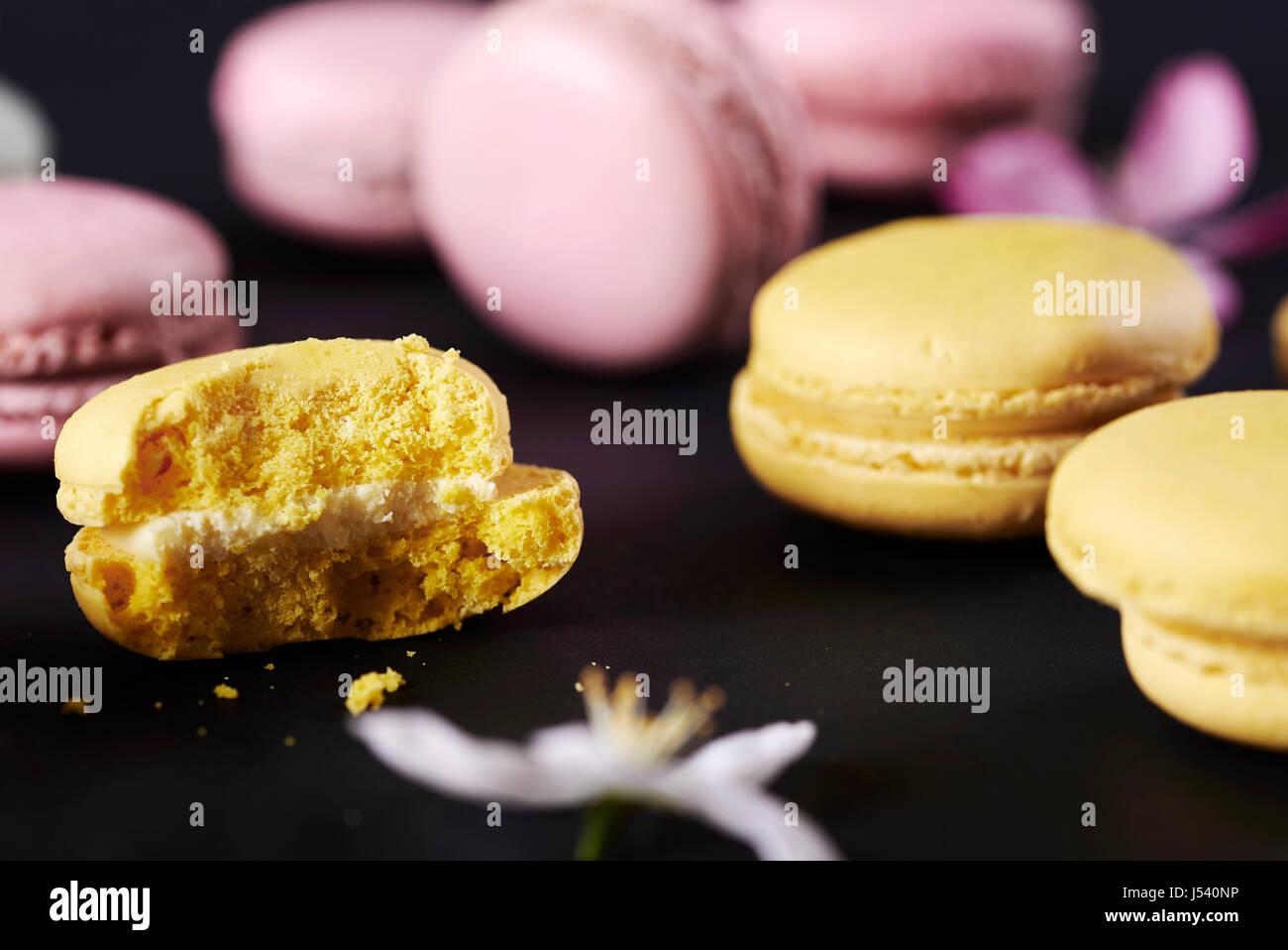 Bitten macaroon among colorful snacks Stock Photo - Alamy