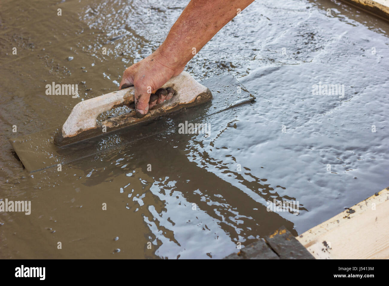 hand spreading poured concrete and leveling concrete with trowel Stock ...