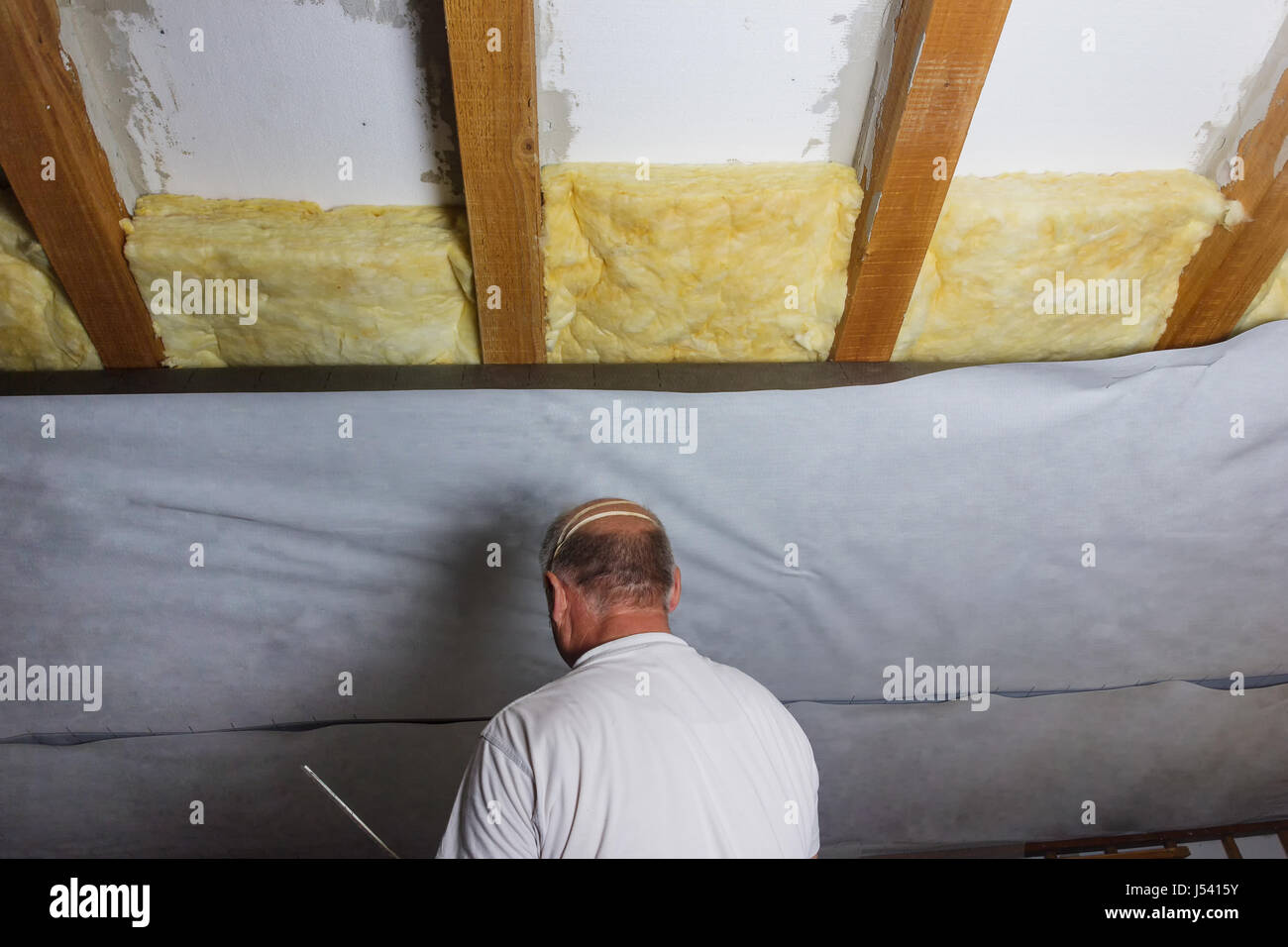 wooden beams of attic with thermal insulation fitting in there and foil ...