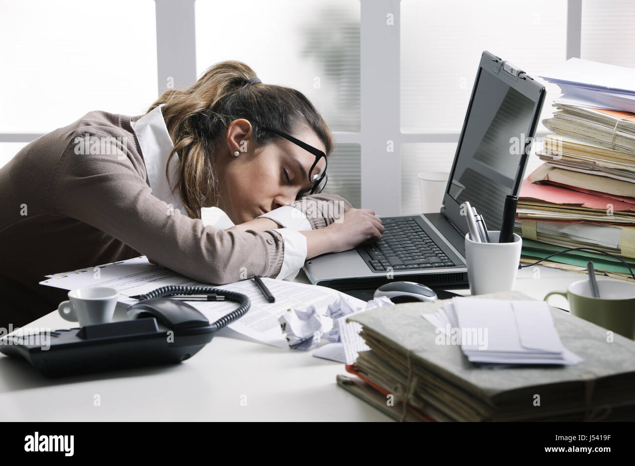 Tired businesswoman sleeping on the desk, in front of the computer ...