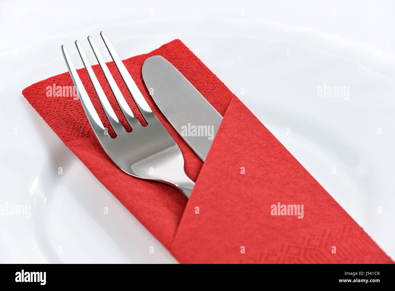 Cutlery in a red folded napkin on plates in the restaurant Stock Photo ...