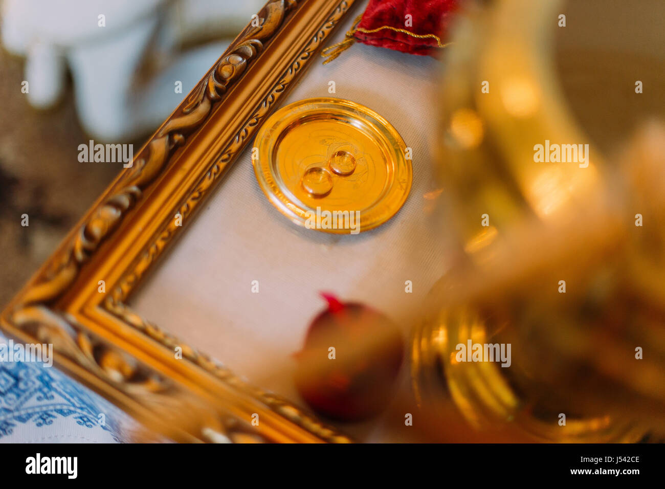 Two golden wedding rings in ceremonial bown on church altar with ...