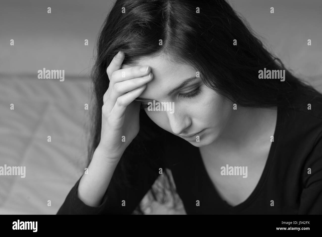 Sad depressed woman touching her forehead and looking down, stress and ...