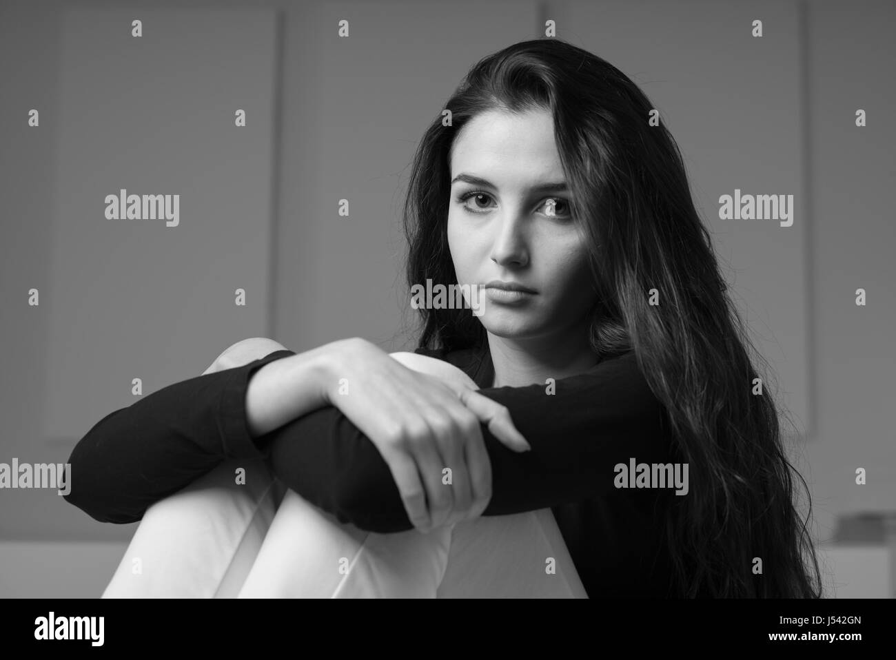 Pensive young girl sitting and posing, she is staring at camera Stock ...