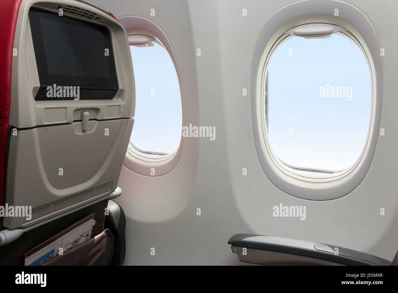 back of seat with a monitor beside the window of a flying airplane ...
