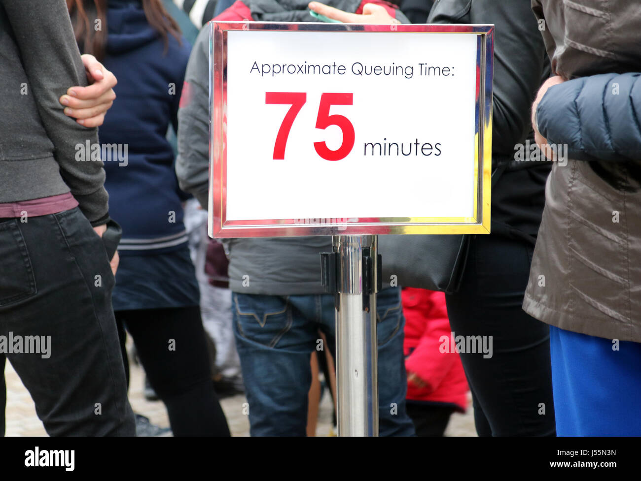 People waiting in a long queue, focus on the information sign ...