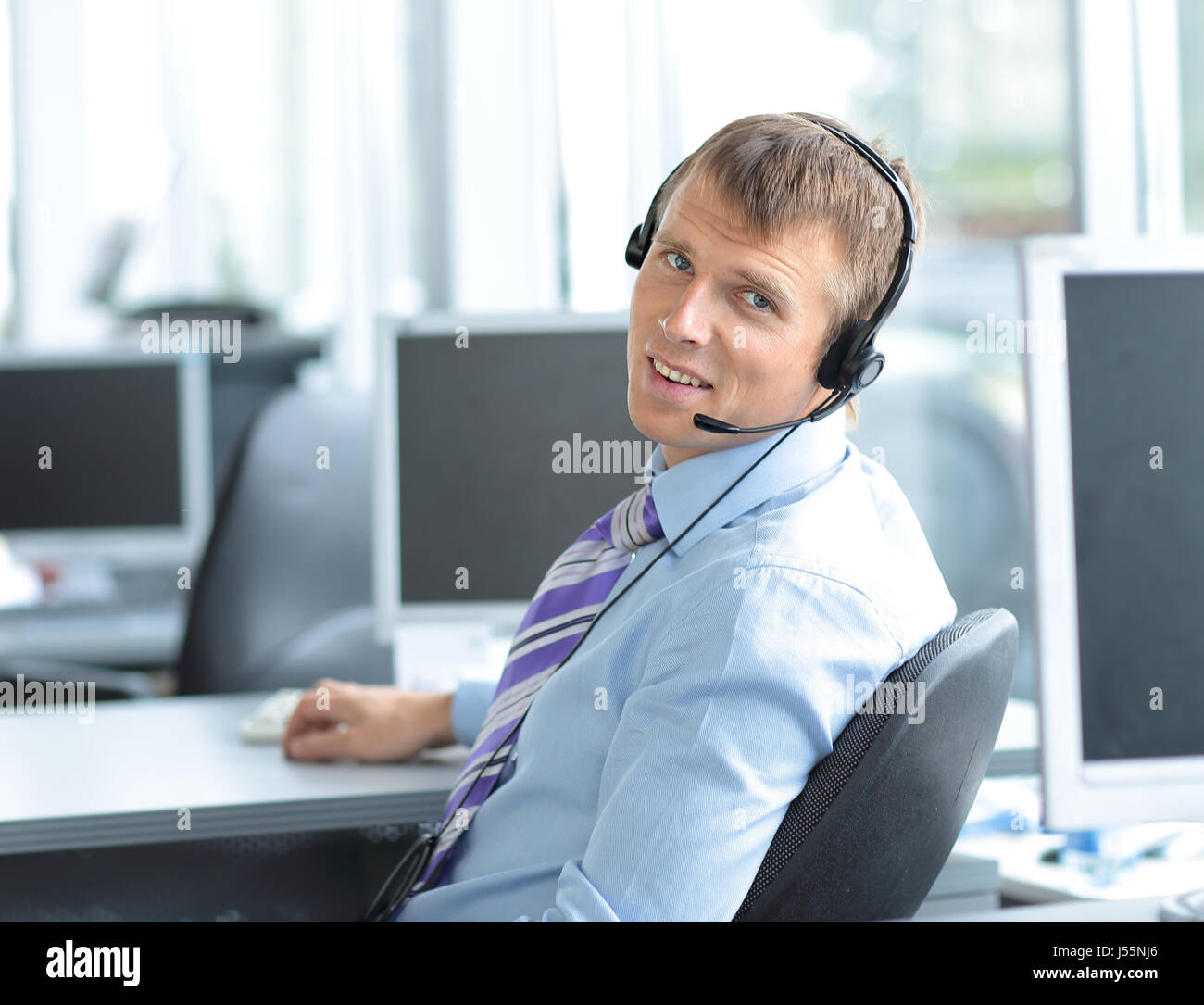 Businessman using headphones and smiling at office Stock Photo - Alamy