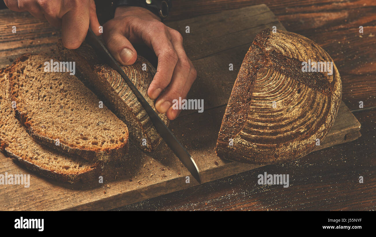 Baker man slices bread Stock Photo - Alamy