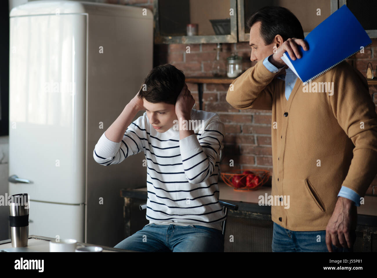 Angry father lifting his arm with copybook on son Stock Photo - Alamy
