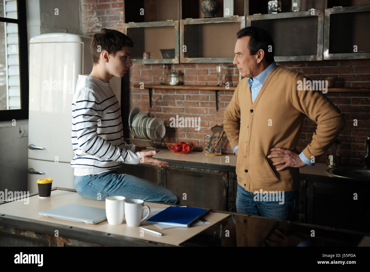 Delighted boy sitting on the table Stock Photo - Alamy