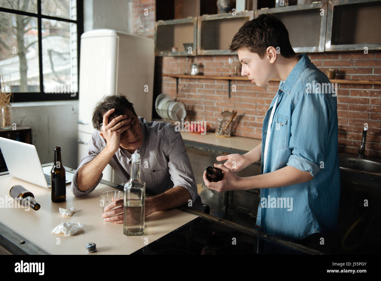 Serious boy talking to his drunk father Stock Photo - Alamy