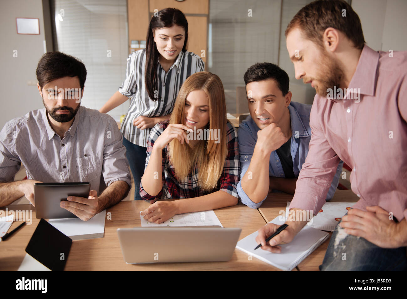 Attentive young people thinking about project Stock Photo - Alamy