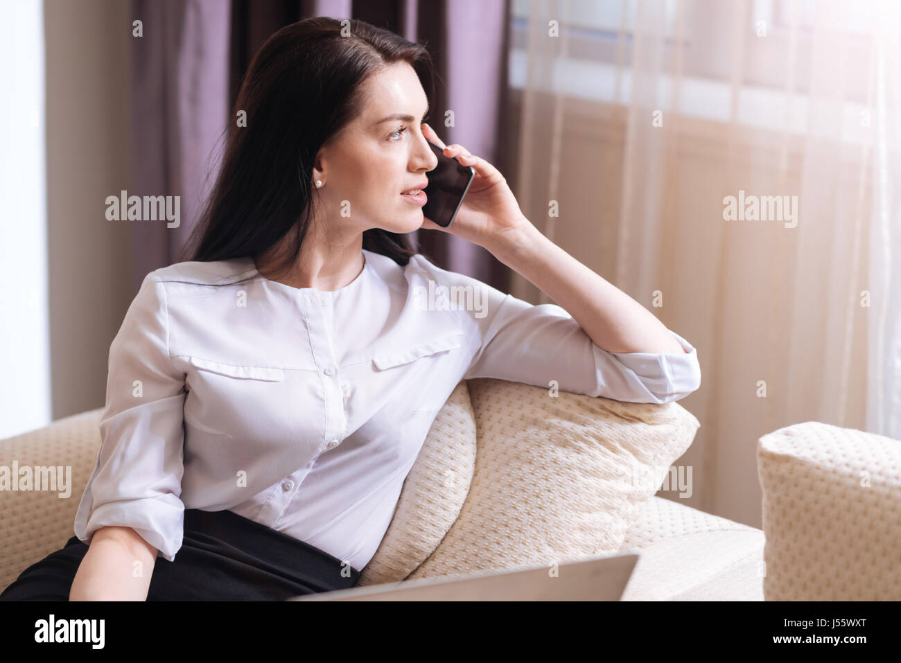 Beautiful serious woman putting a phone to her ear Stock Photo - Alamy