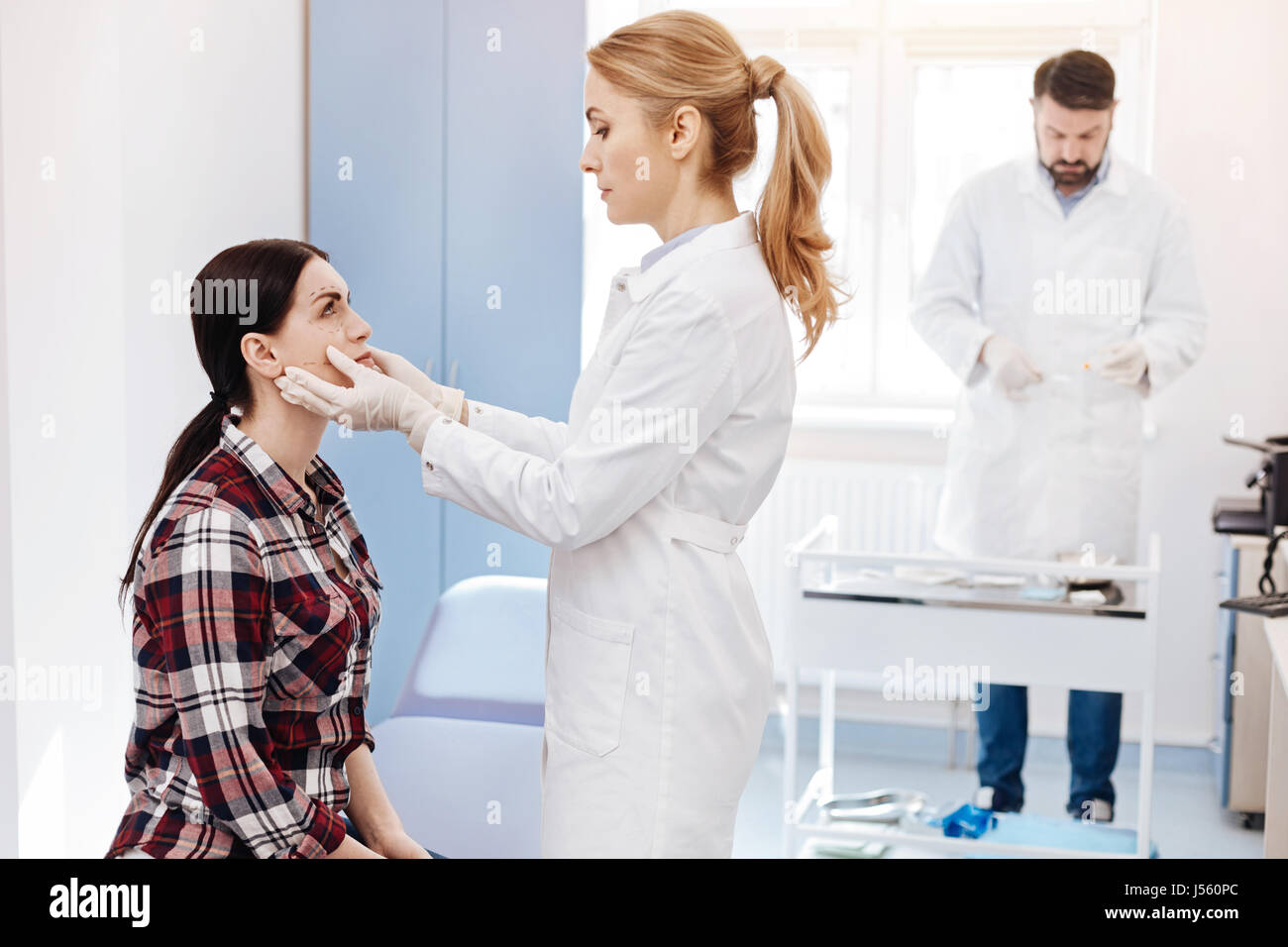 Nice plastic surgeon holding her patients face Stock Photo - Alamy