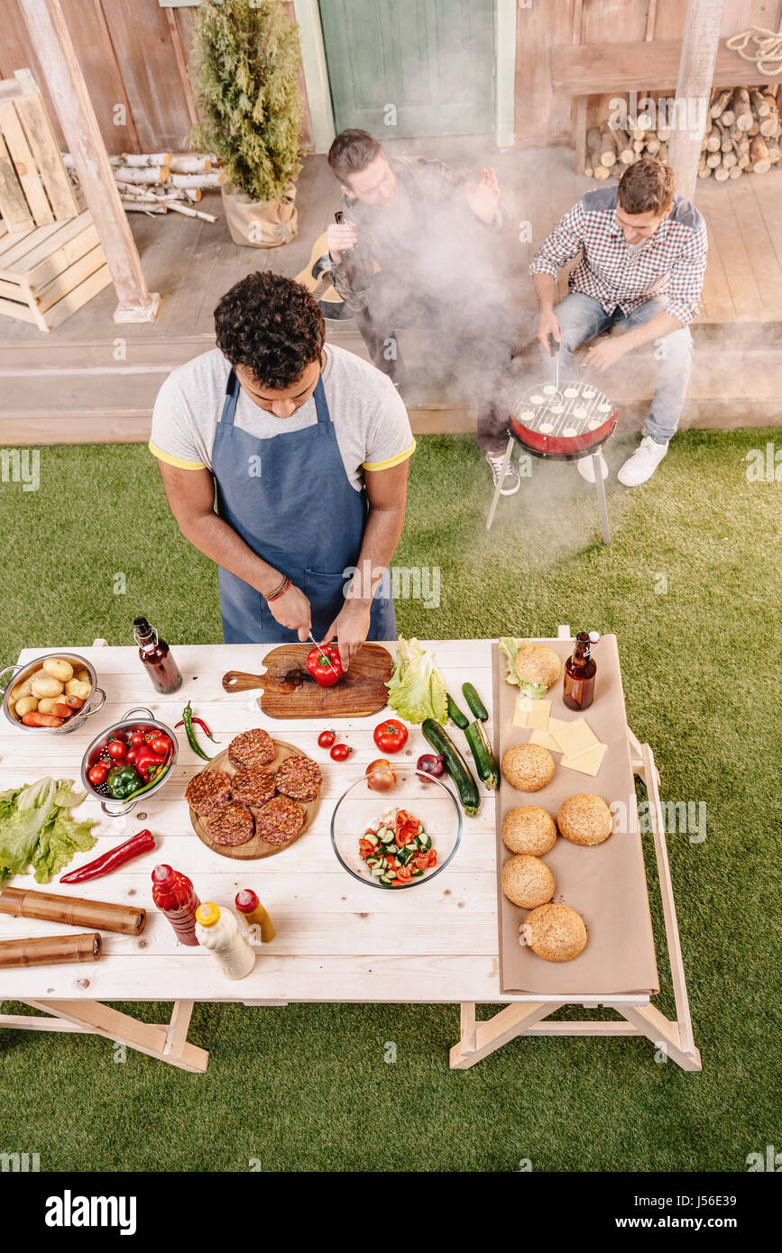 man making burgers while his friends sitting behind on porch Stock ...