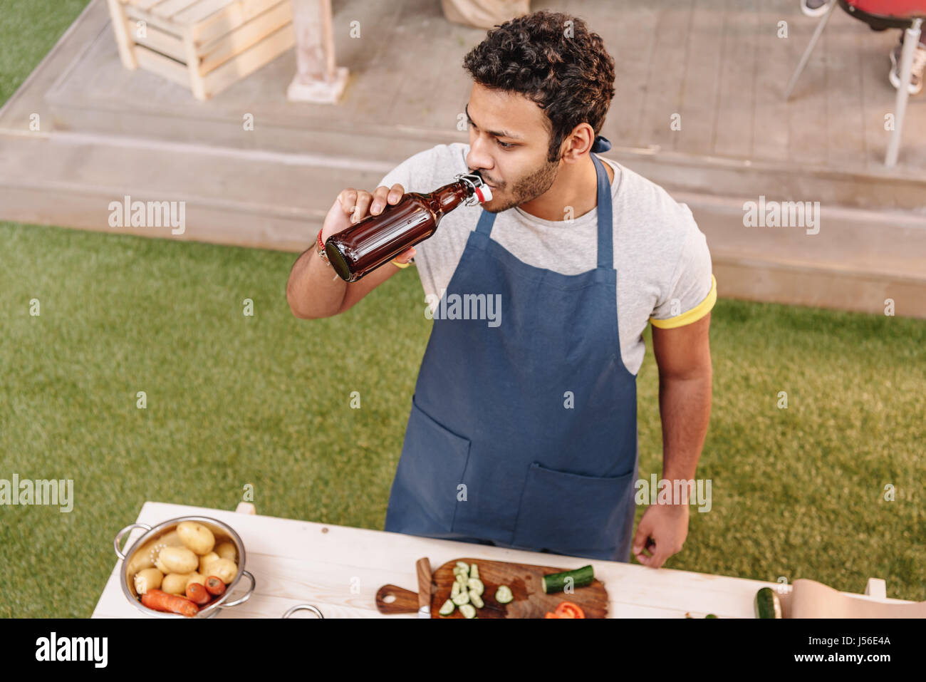 man making burgers and drinking beer from bottle outdoors Stock Photo ...