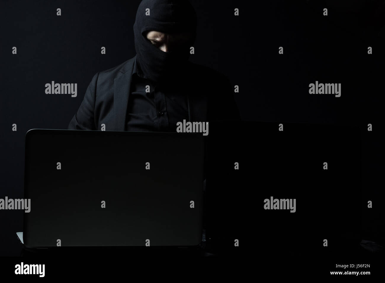 Angry business man as computer hacker in suit stealing data from laptop ...