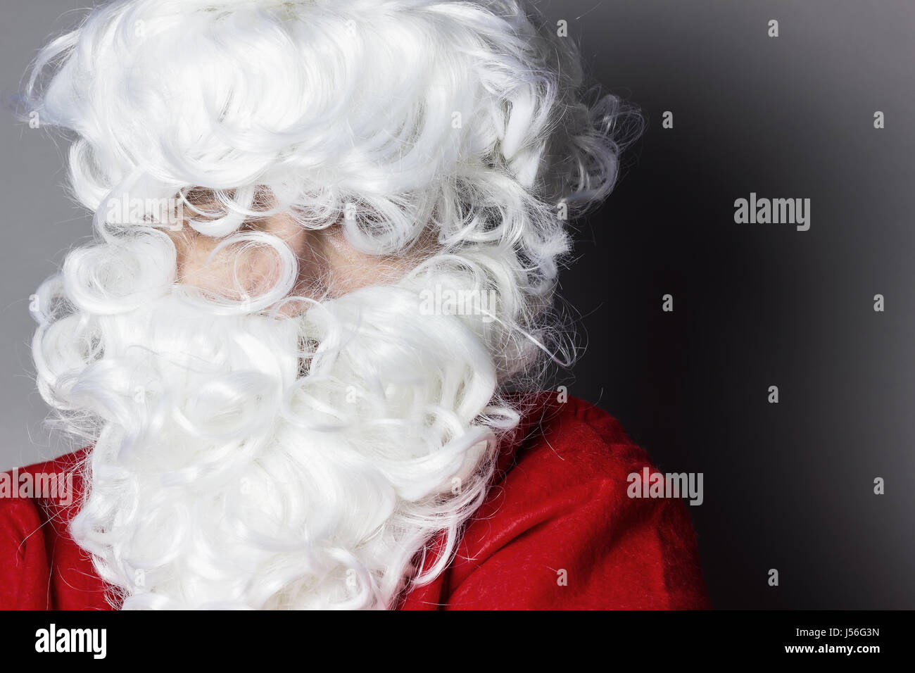 portrait of santa claus with tousled hair and beard in front of grey ...